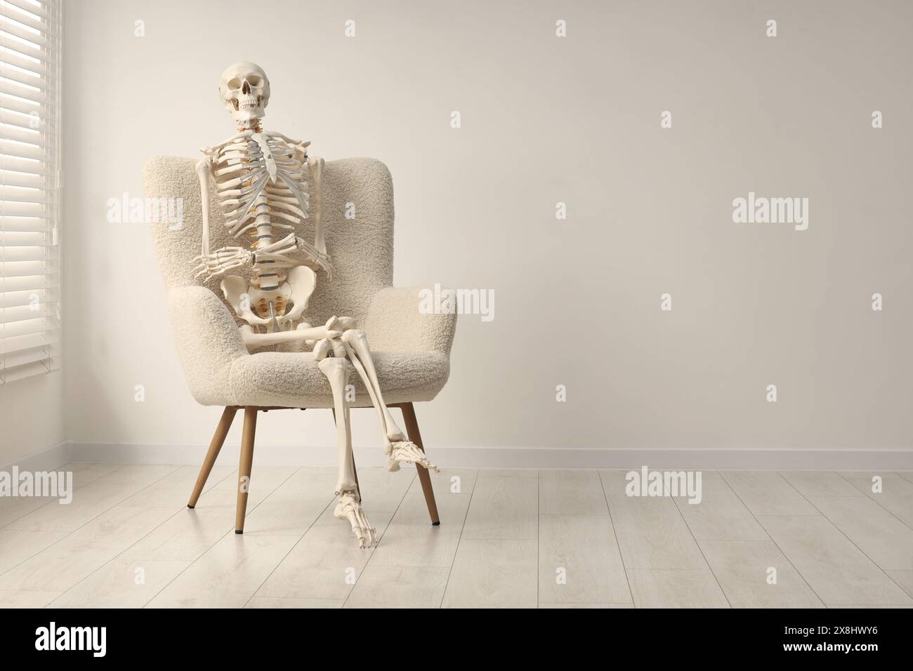 Waiting concept. Human skeleton sitting in armchair indoors, space for ...