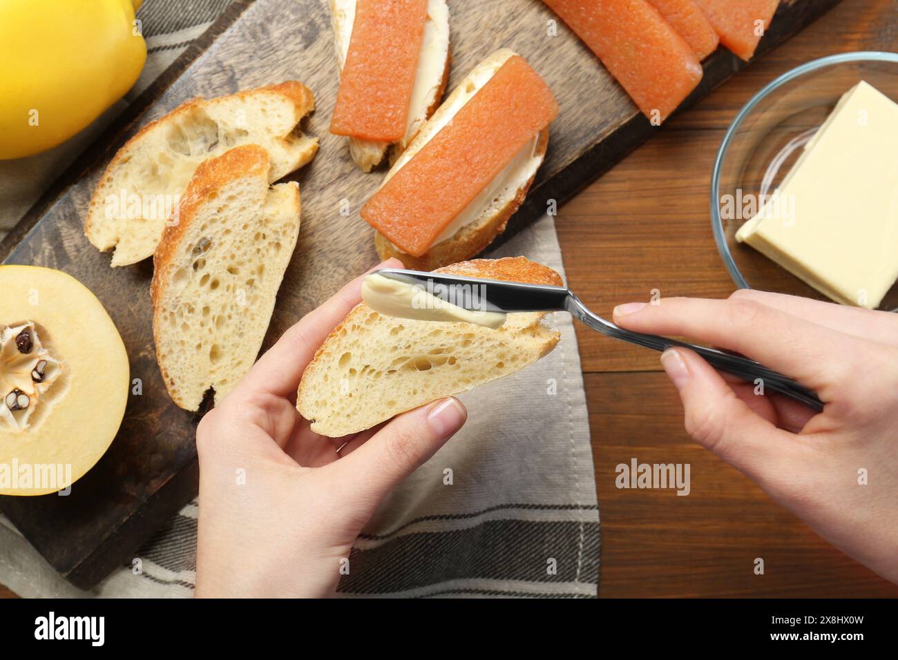Making sandwich with quince paste. Woman buttering bread at wooden ...