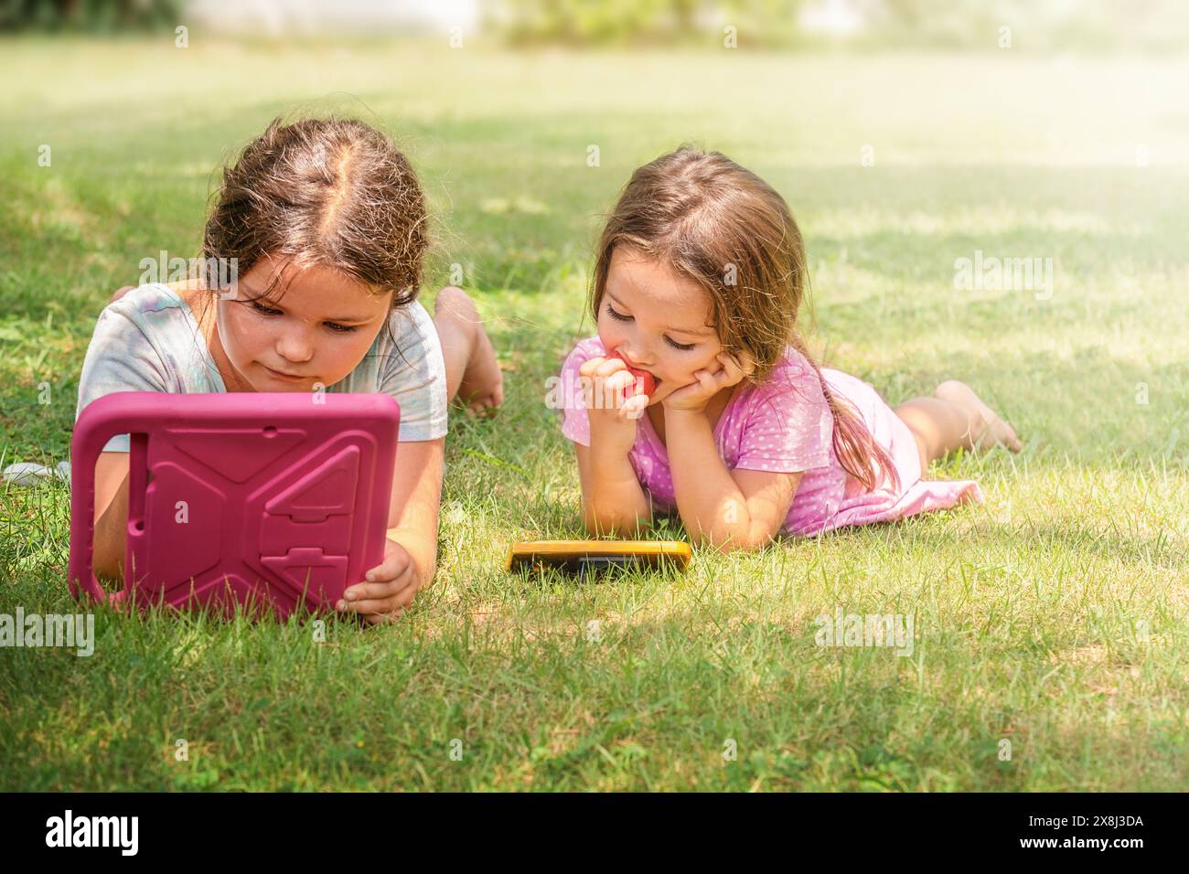 Children playing tablet and phone in the backyard in summer Stock Photo ...