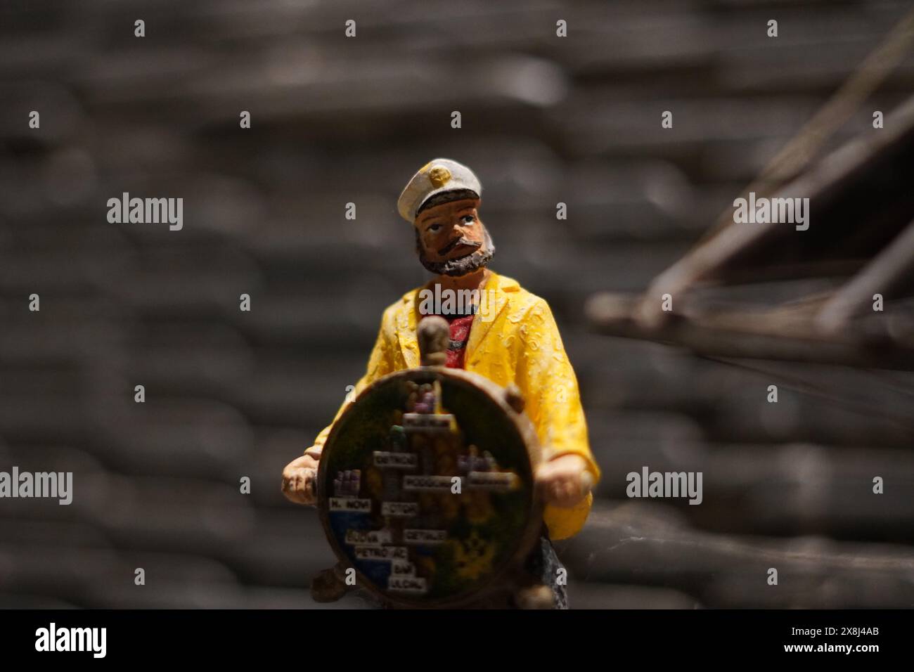 Figure of a sailor holding the steering wheel of a ship with the words ...