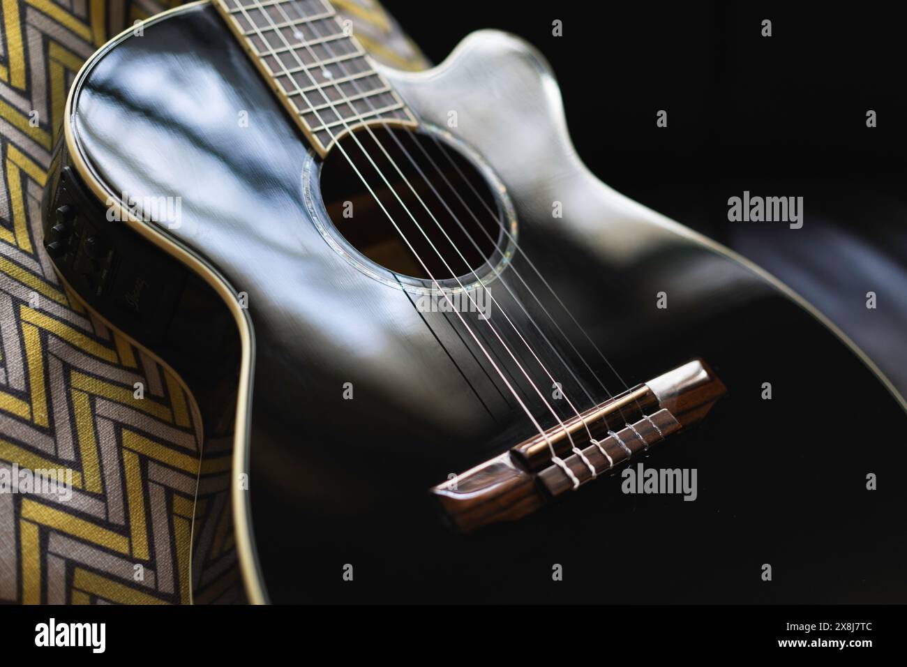 Acoustic guitar resting on black leather sofa by the living room window ...