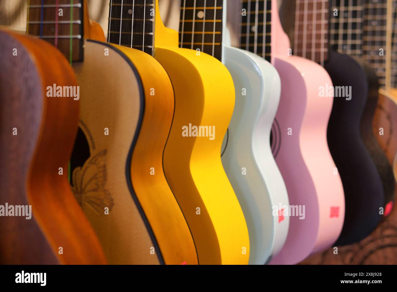 Row of colorful guitars hanging Stock Photo - Alamy