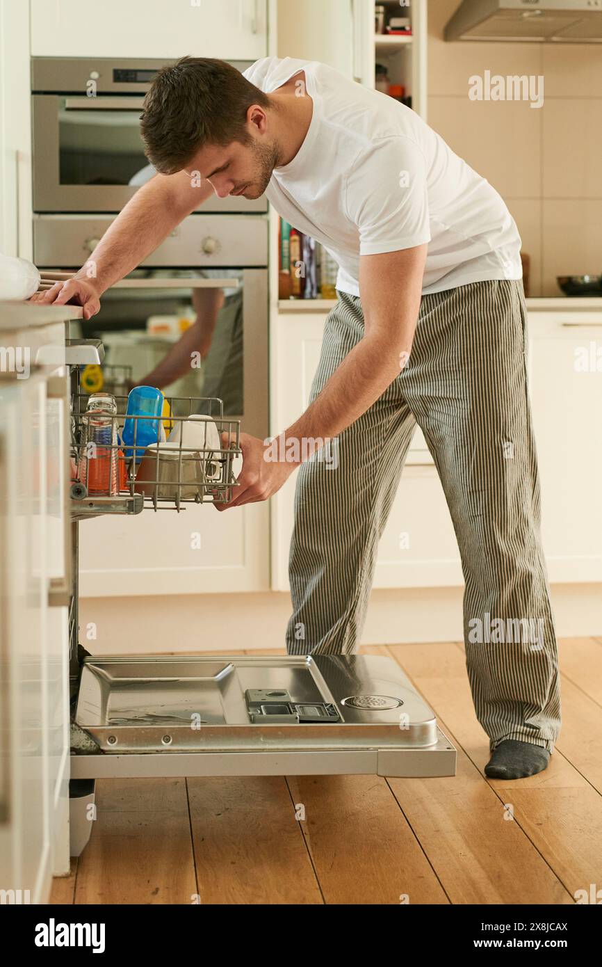 Man, kitchen and washing dishes with dishwasher for cleaning, hygiene ...