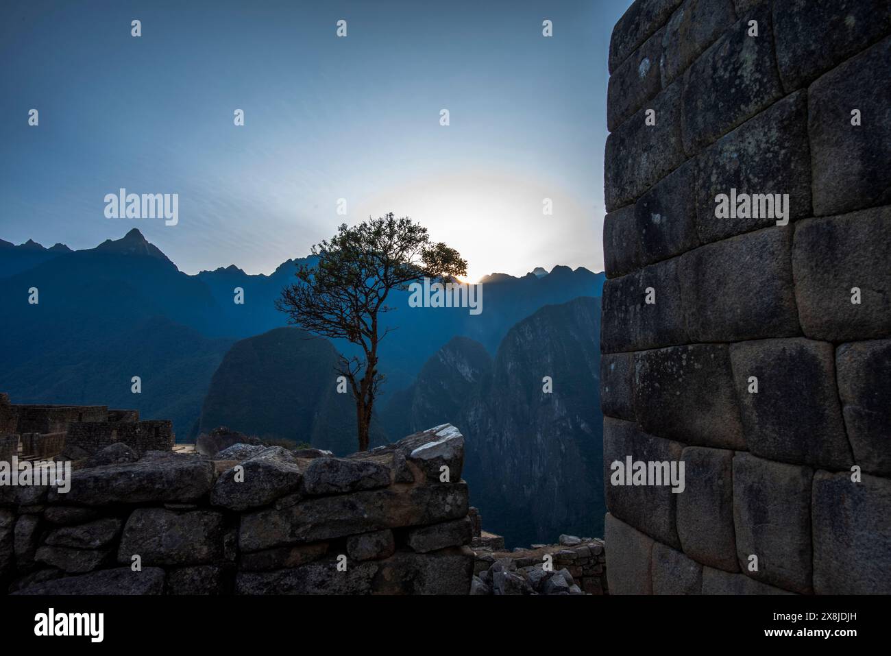 sunrise among the trees and Inca ruins with the mountain peaks of the ...