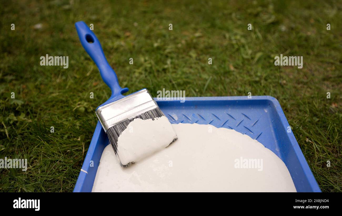 Bright yellow paint is poured into the tray. Paint is poured from a ...