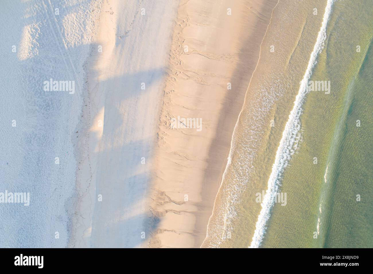 shore of a beach at sunrise in summer as seen from a drone, directly ...