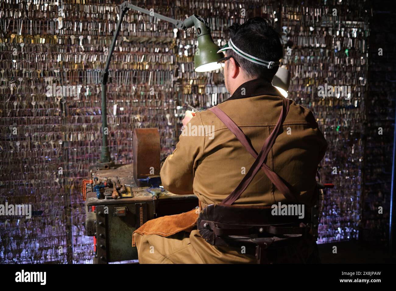 Male locksmith working diligently at desk surrounded by hundreds of ...