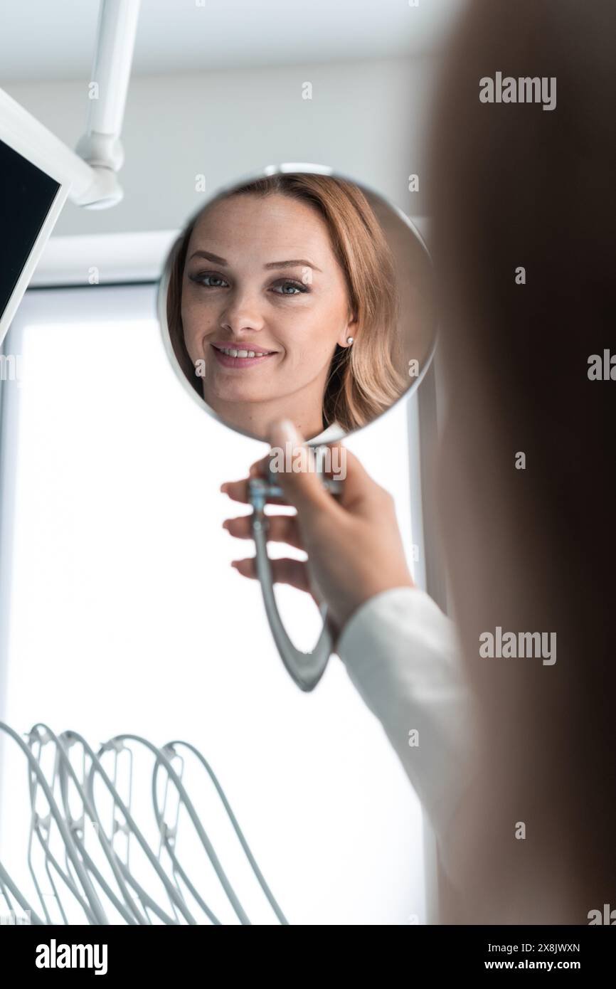 The patient, posing with a mirror in her hands, demonstrates her ...