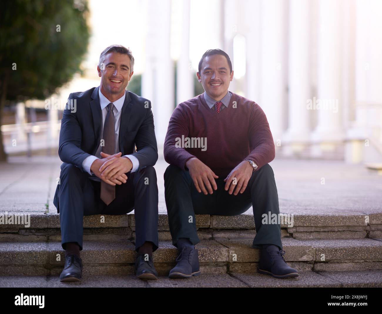 Business men, partner and sitting on stairs in portrait, city and smile ...