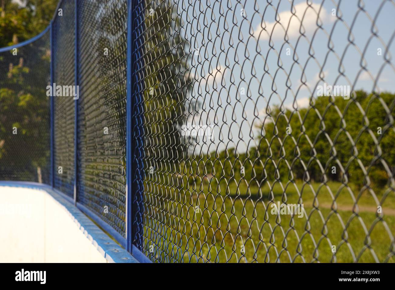 A close-up shot of a blue chain link fence of sports ground in a park ...