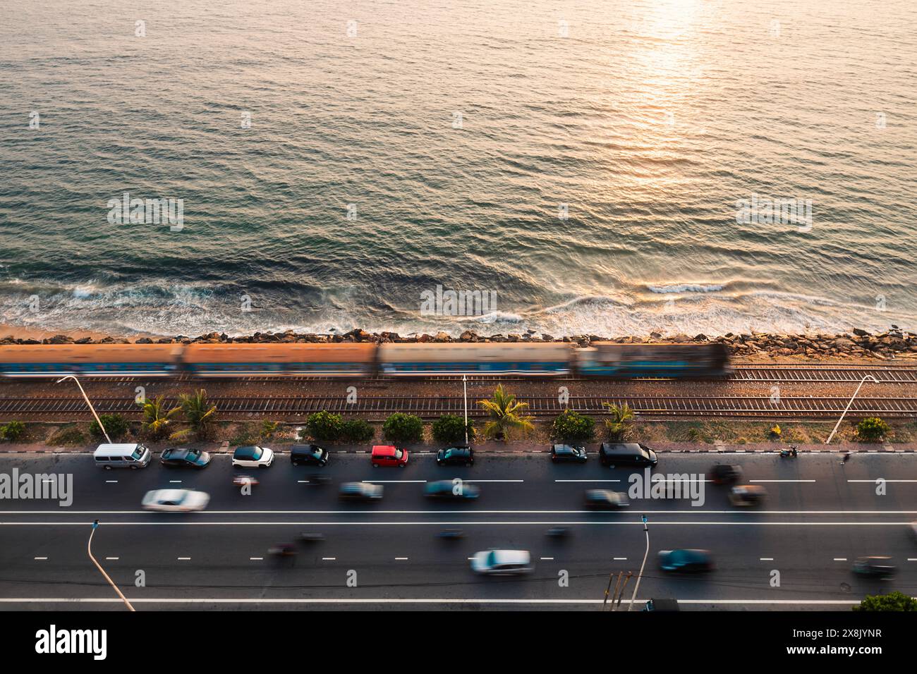 Road and railway track along coast at sunset over Indian ocean. Train ...