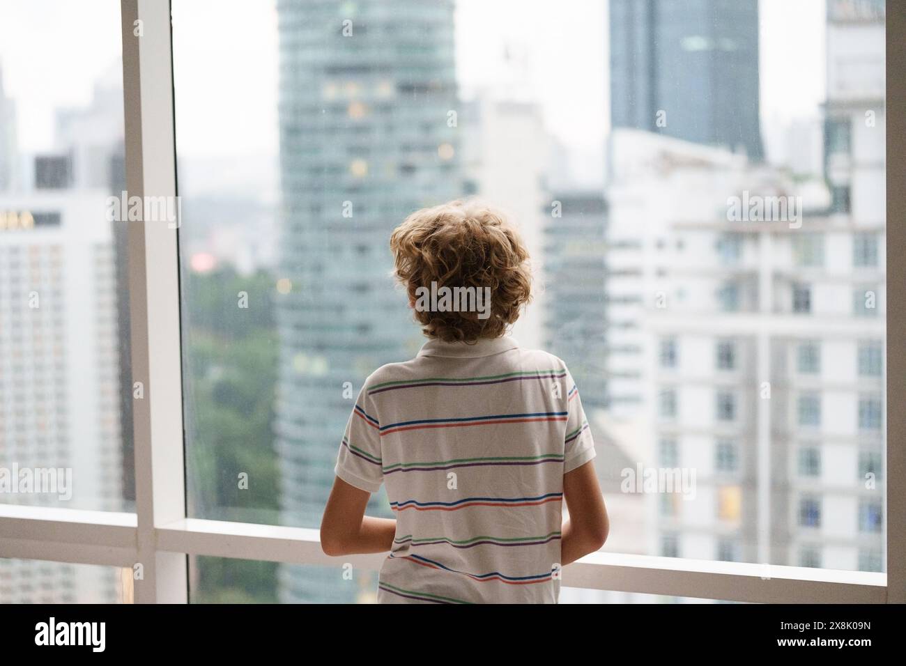 Child at a large window. Home safety. Safe lock on windows in high rise ...
