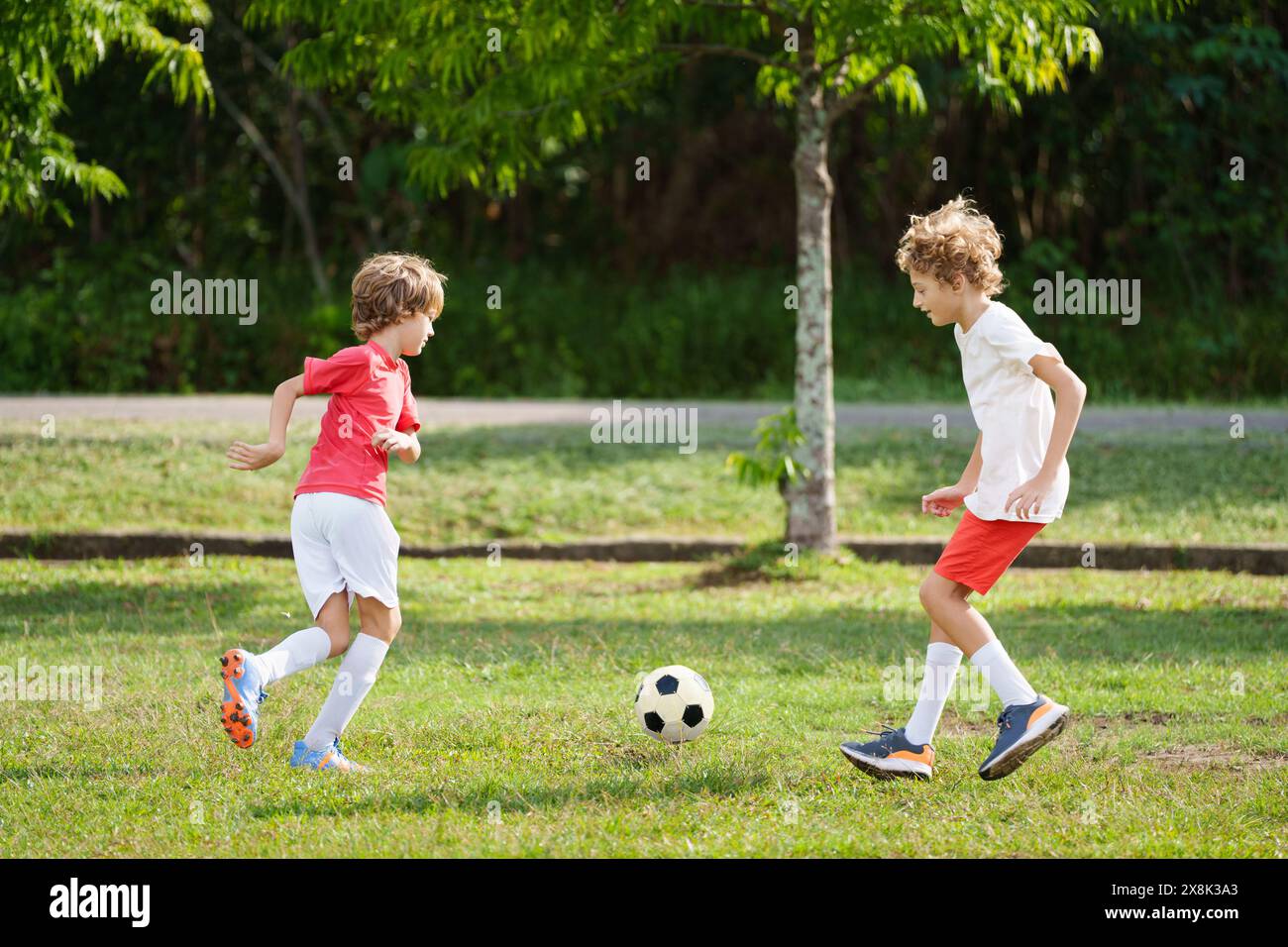 Child playing football. Kids play soccer on outdoor pitch. Little boy ...