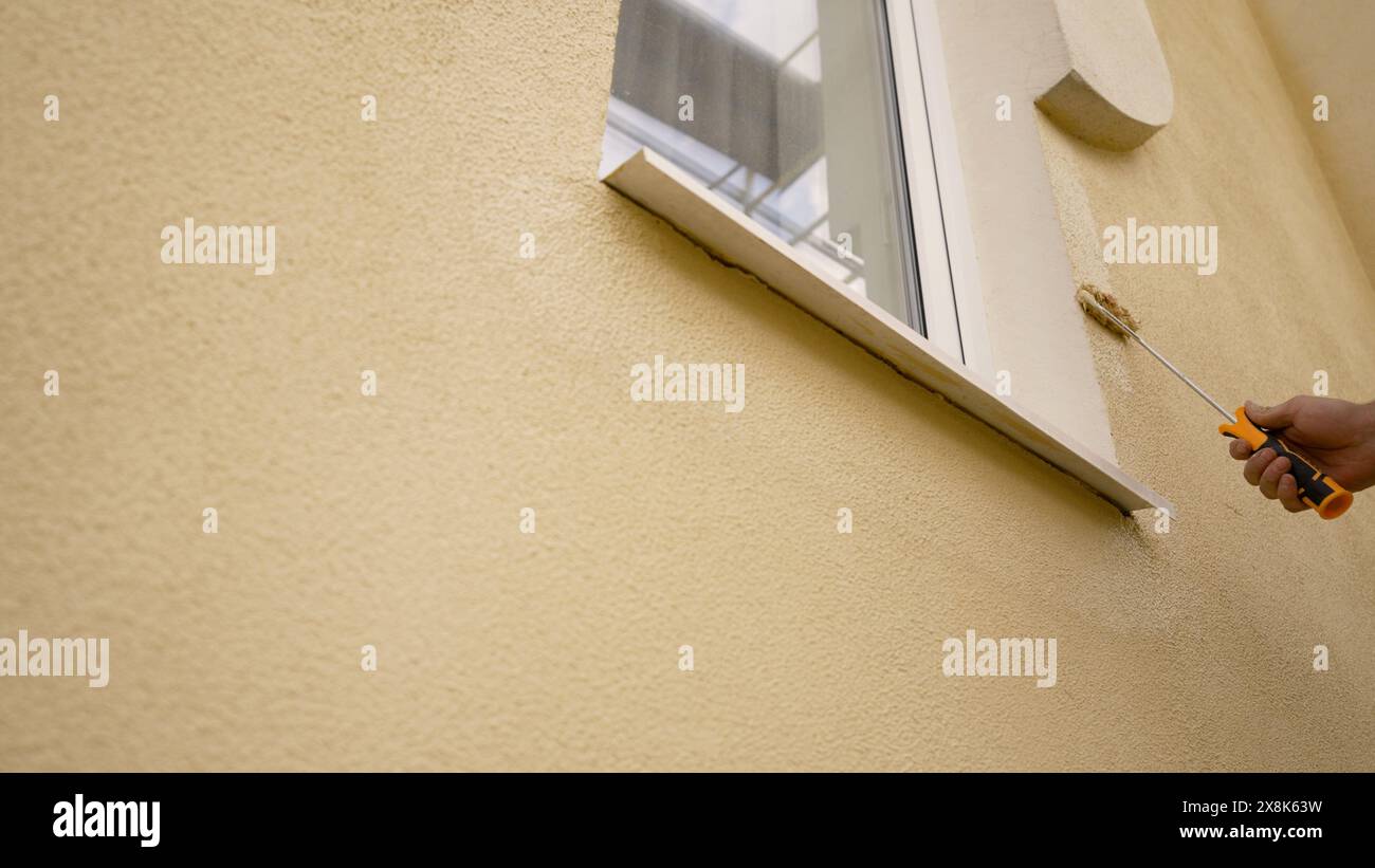 An industrial climber primes the wall of a building with a roller. The ...