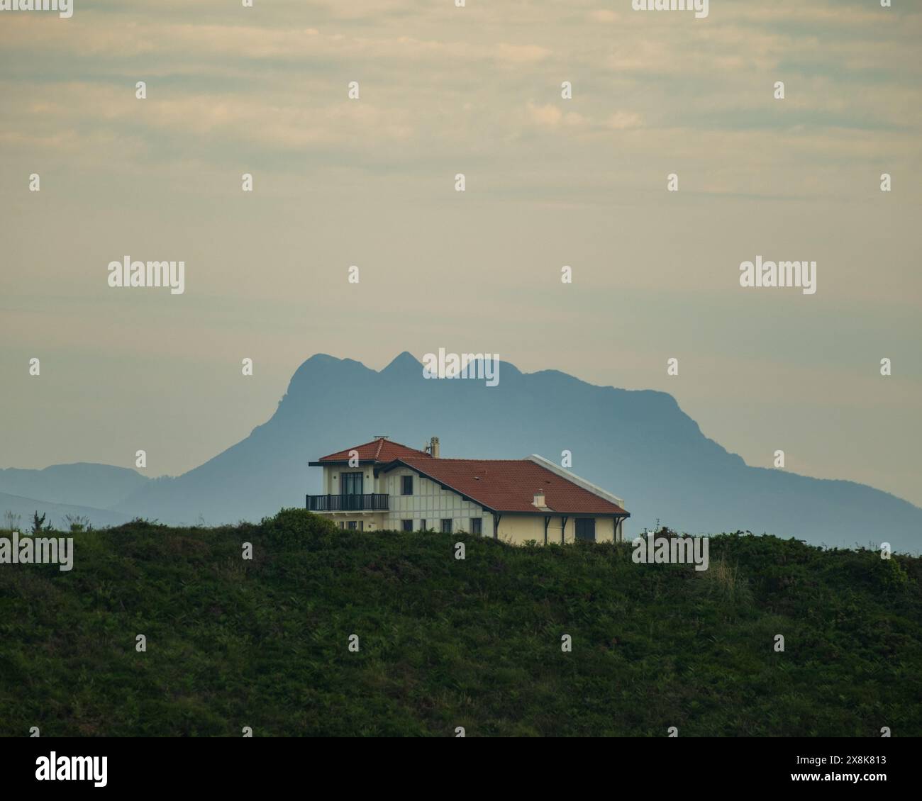 telephoto photo of a house located in front of a mountain with large ...