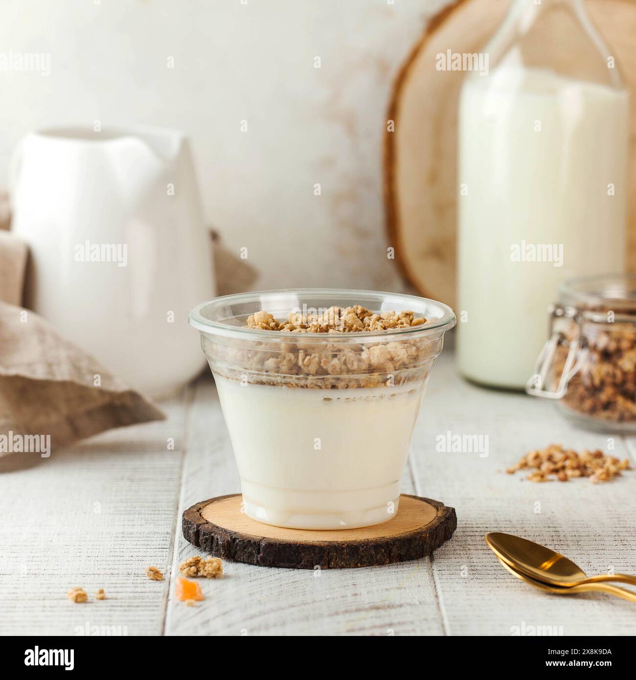 Natural yogurt topped with crunchy muesli in a clear cup with a milk ...