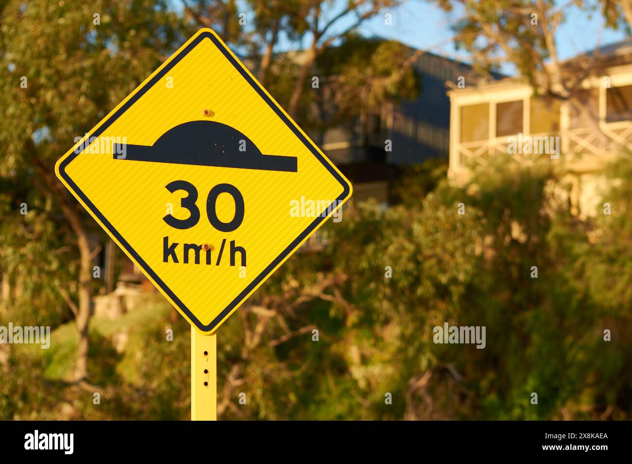 A sign indicating a speed bump ahead, advising to slow down and drive ...
