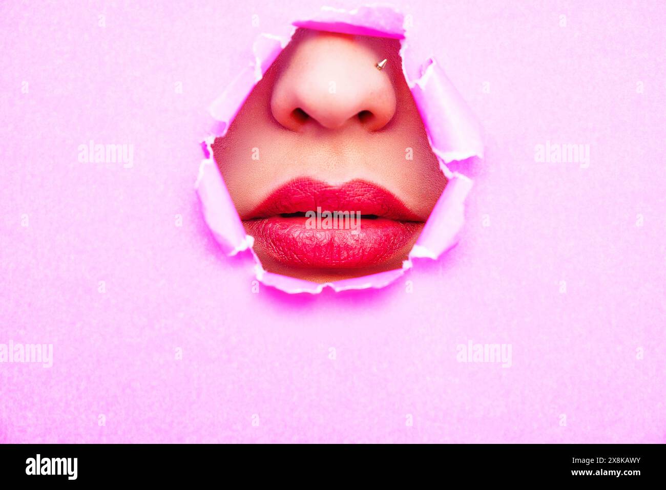 A woman's nose and mouth are visible through pink torn paper Stock ...