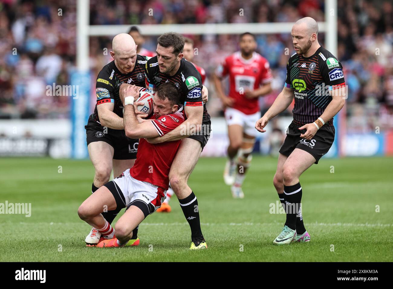 Ryan Brierley of Salford Red Devils is tackled by Liam Farrell of Wigan Warriors and Jake Wardle ...