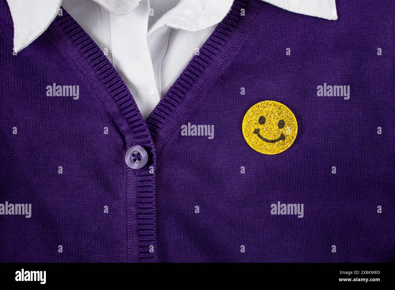 Golden glitter smiley face sticker on a child chest with purple uniform ...