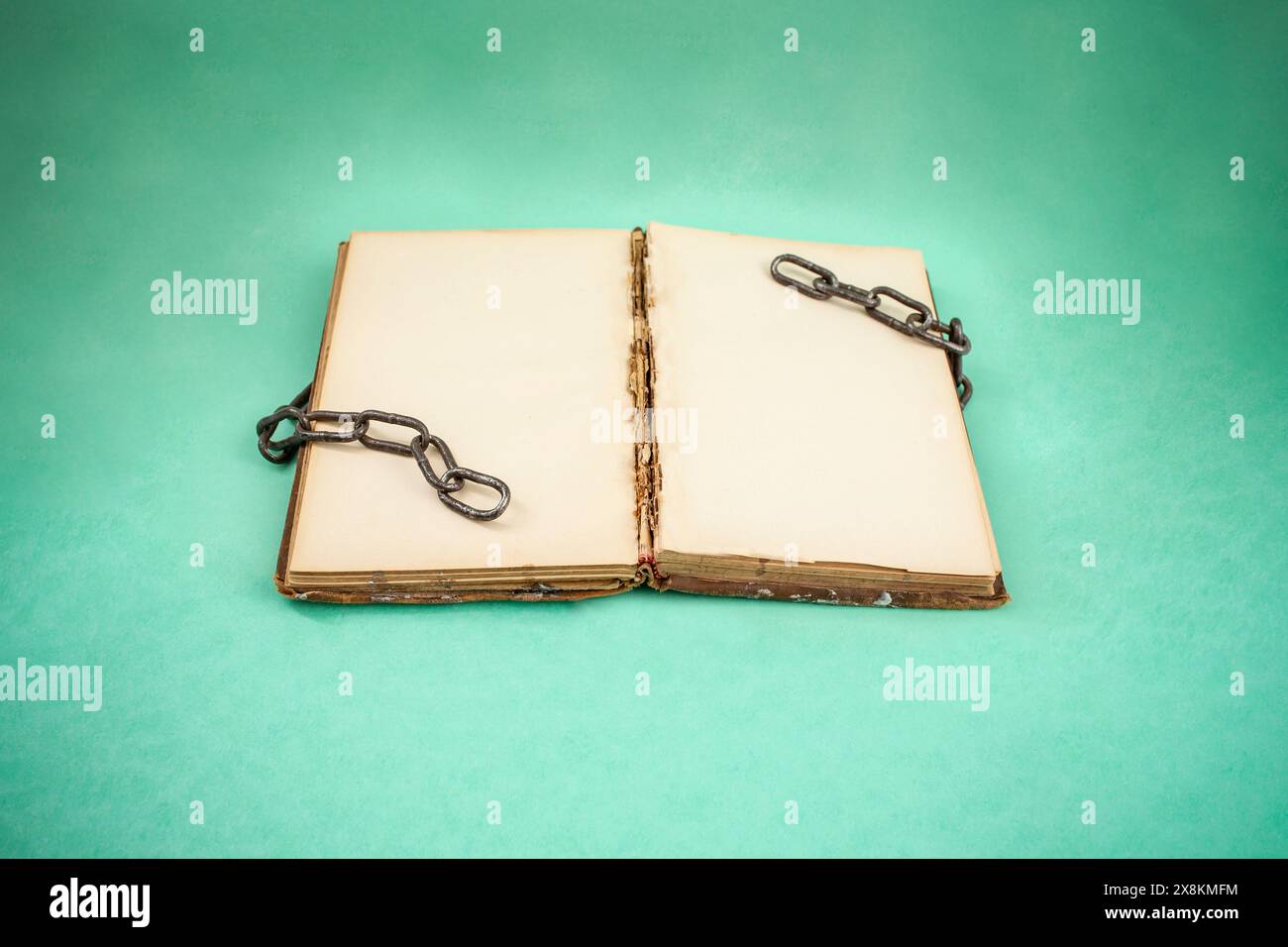 Open book with empty yellowed pages and broken chains in green ...