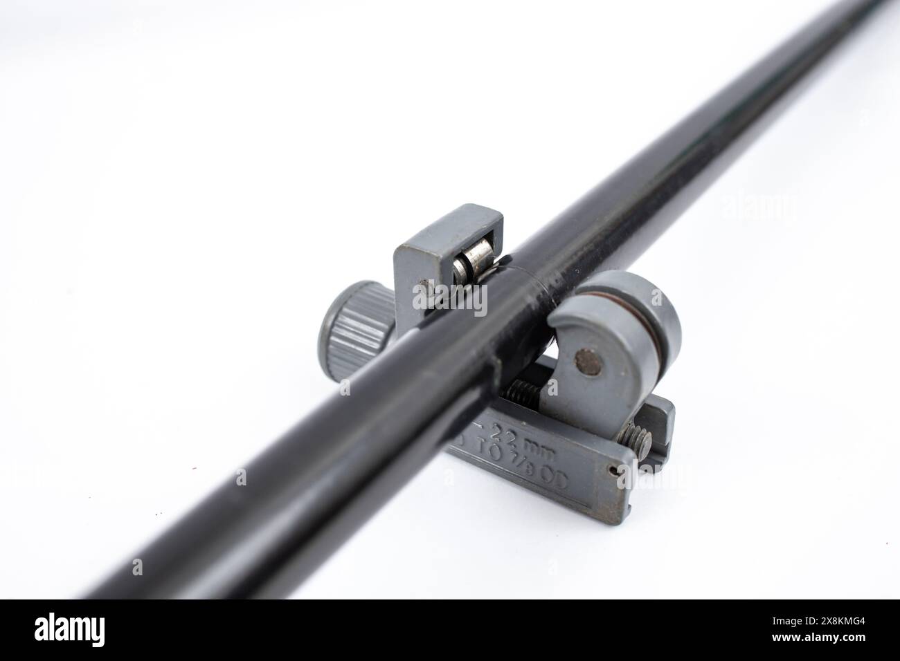 Pipe cutting tool on a black coated copper pipe, isolated on white ...