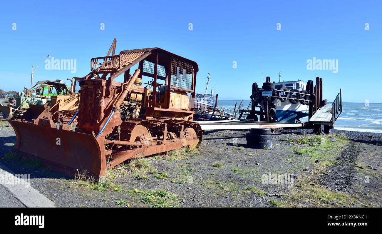 Pirinoa, New Zealand - 05-05-24:Vinatge rusty excavator and boat ...