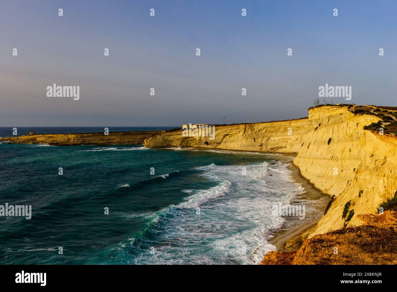 A peaceful beach scene with lush sandstone cliffs, rolling waves, and a ...