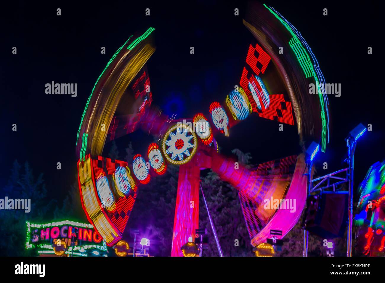 A multi-colored Ferris Wheel lights up the night sky in long exposure ...