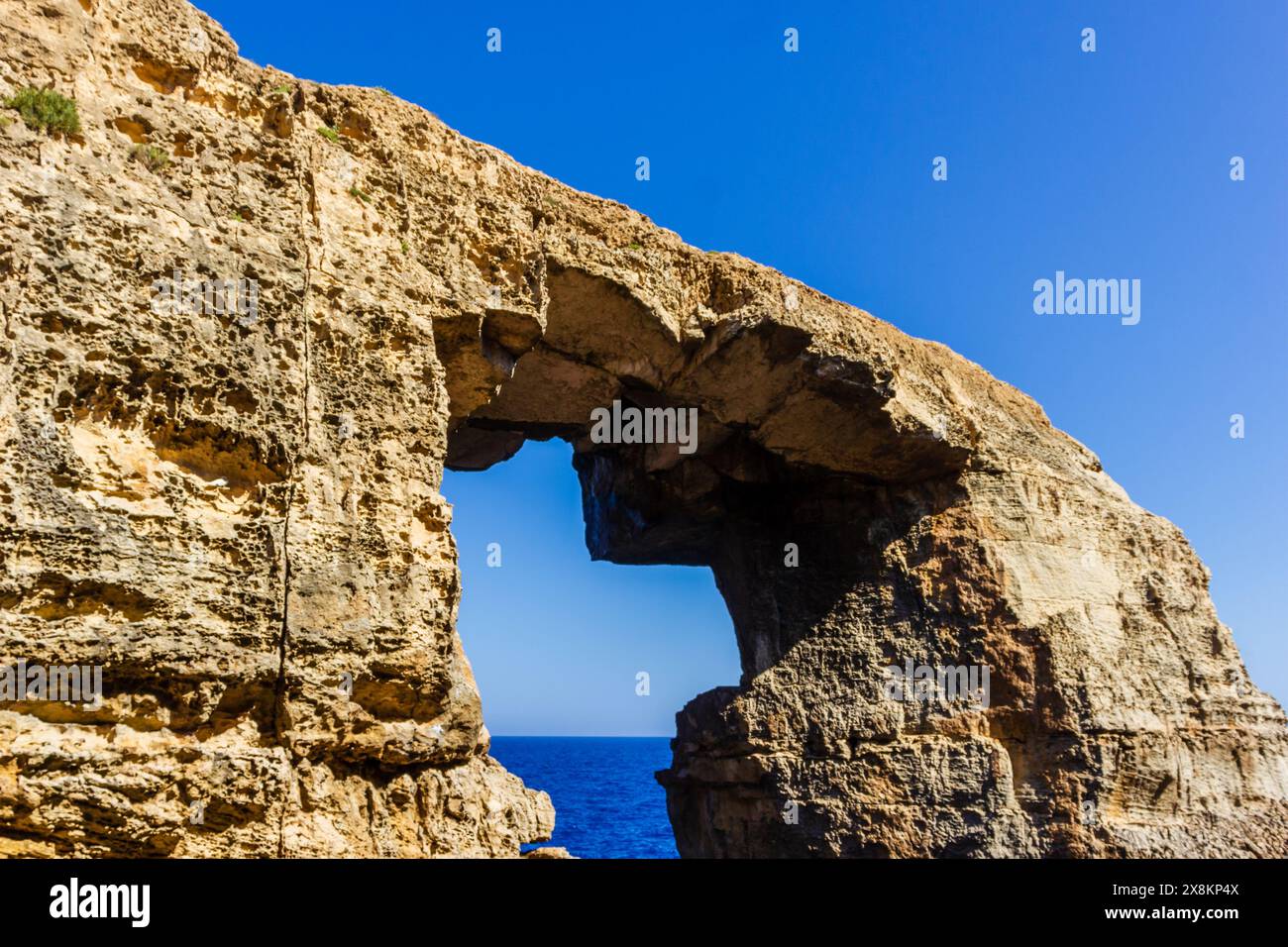 Majestic ancient rock arch on coastal cliff, clear blue sky, serene ...
