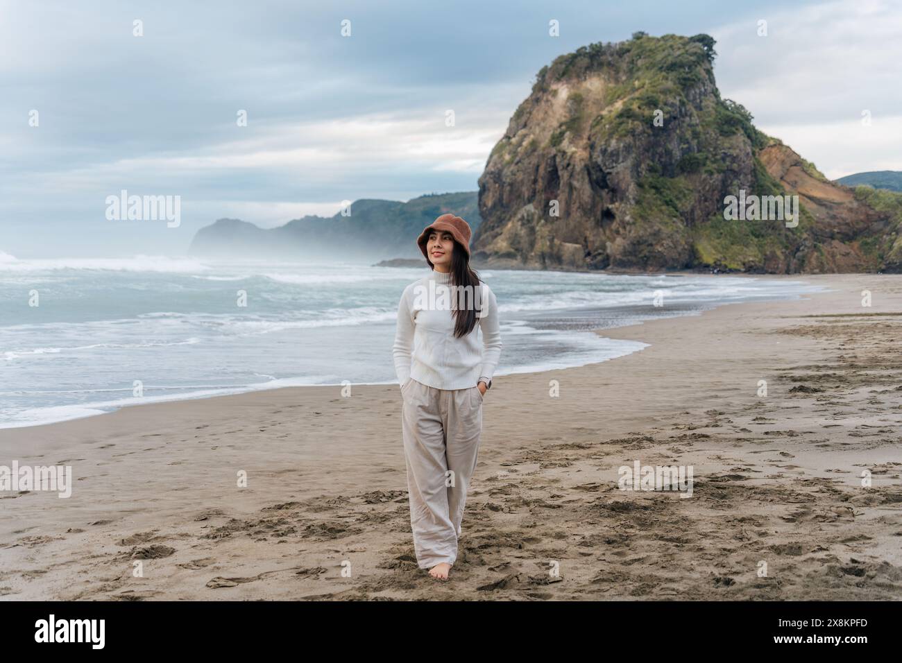 Happy young asian woman enjoying on the Piha Beach with Lion Rock at ...