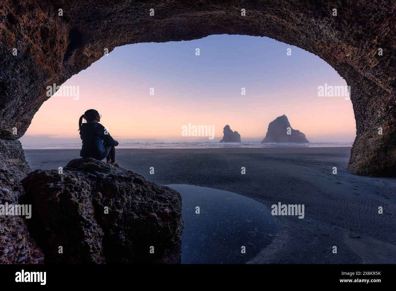 Female tourist sitting on rock in stone cave with Archway islands on ...