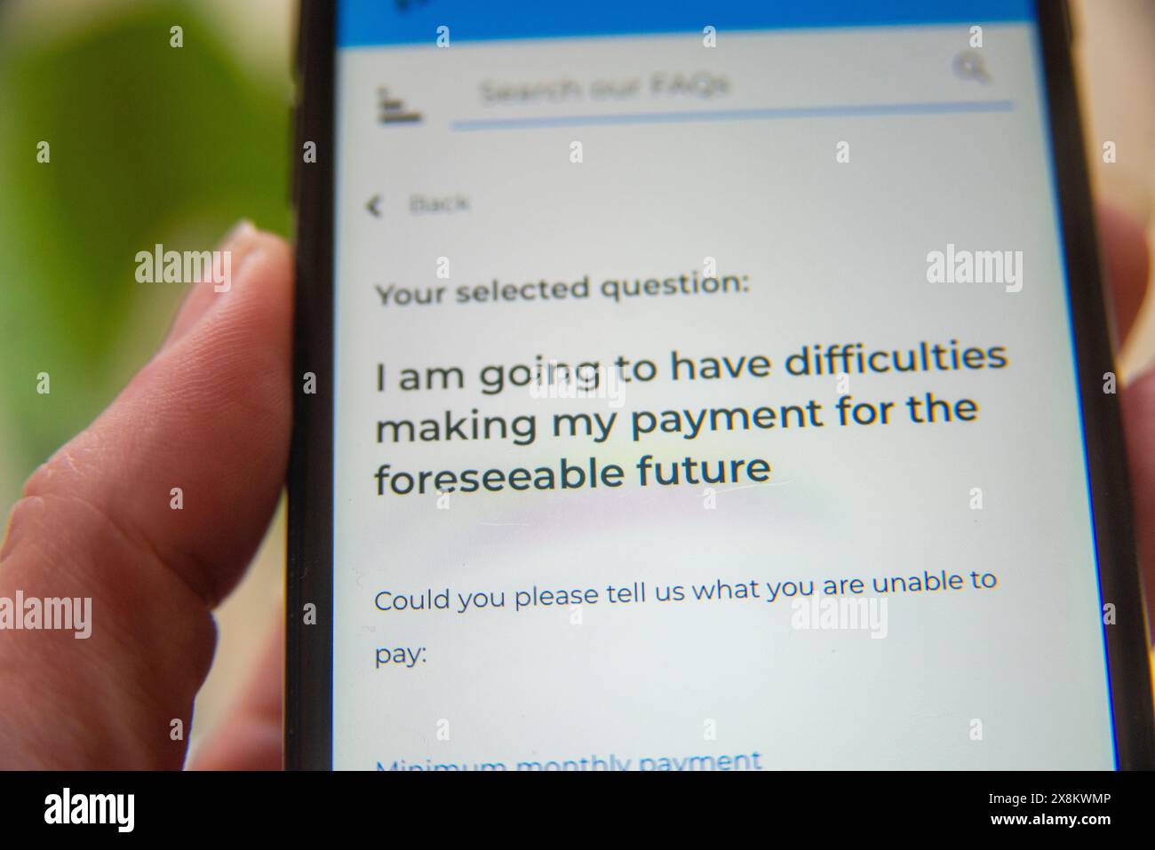 Hand holding a mobile phone displaying an FAQ page about future payment ...
