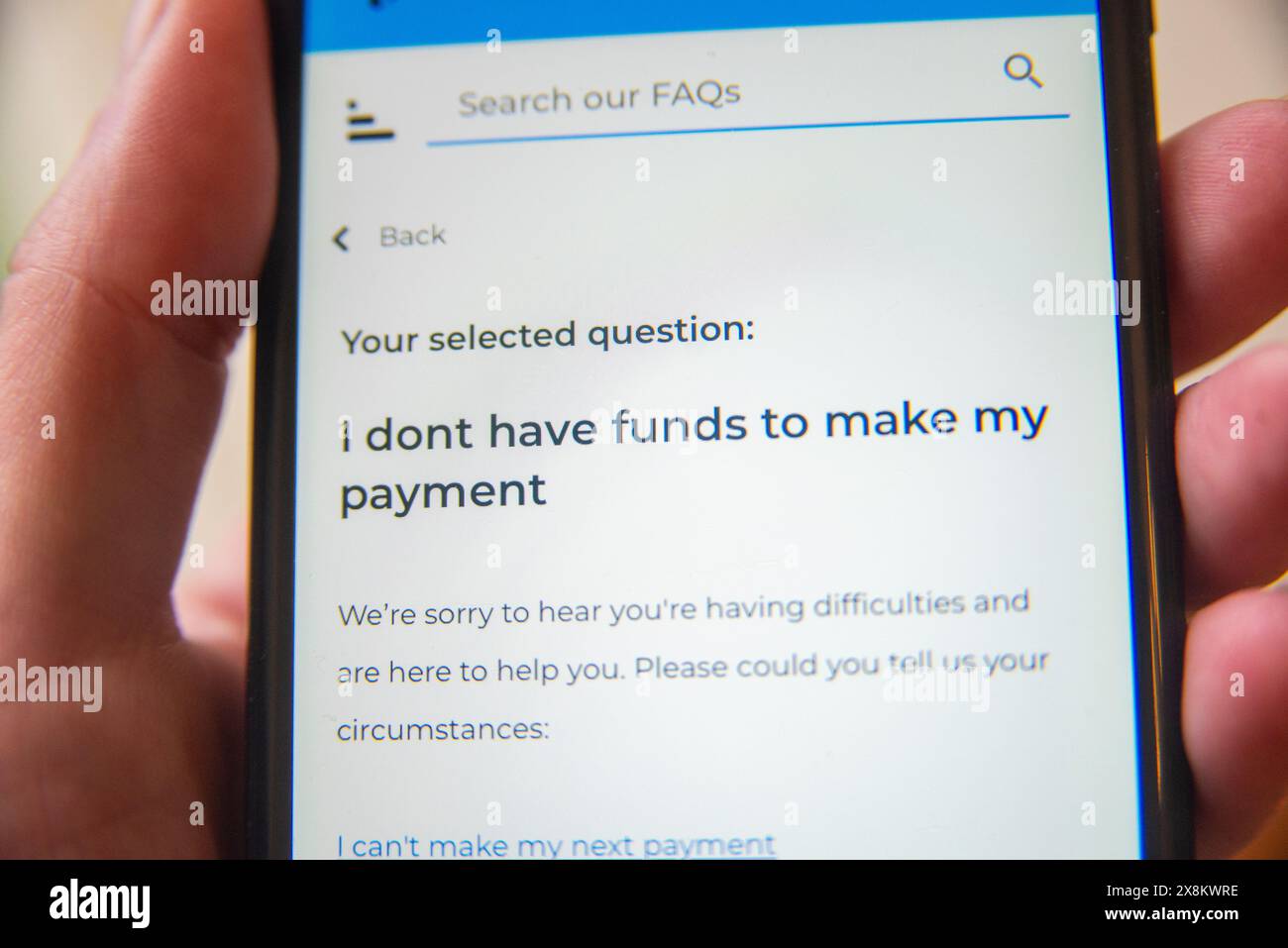 Hand holding a mobile phone displaying an FAQ page about future payment ...
