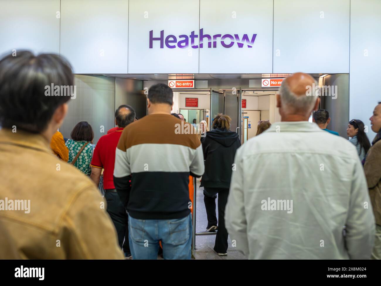 People wait to greet friends and relatives in front of a sign reading ...