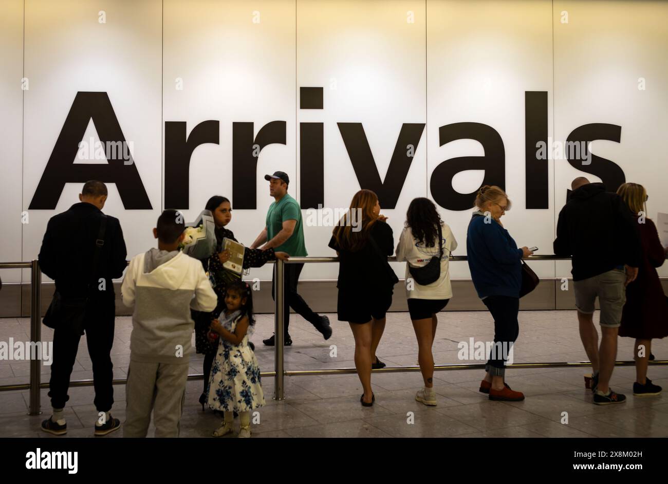 People wait to greet friends and relatives in front of a huge sign ...