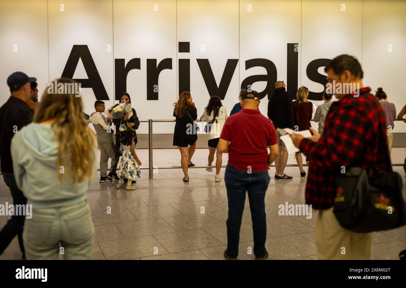 People wait to greet friends and relatives next to a huge sign reading ...