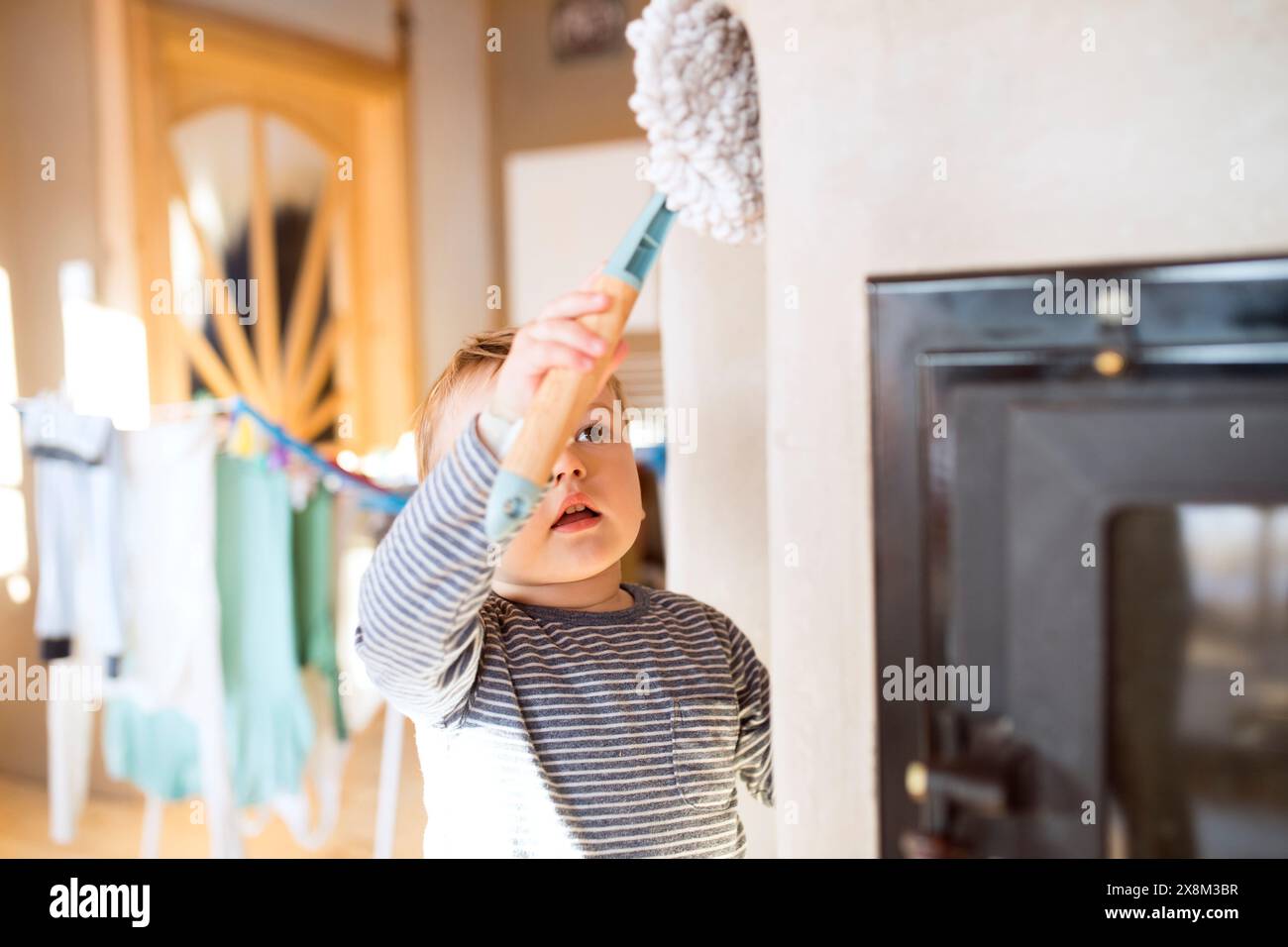 Little boy helping mother with hosehold chores, dusting cleaning their ...