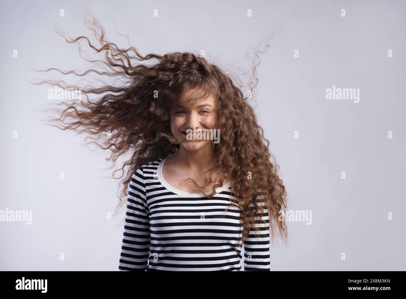 Portrait of a gorgeous teenage girl with curly hair, blowing in wind ...
