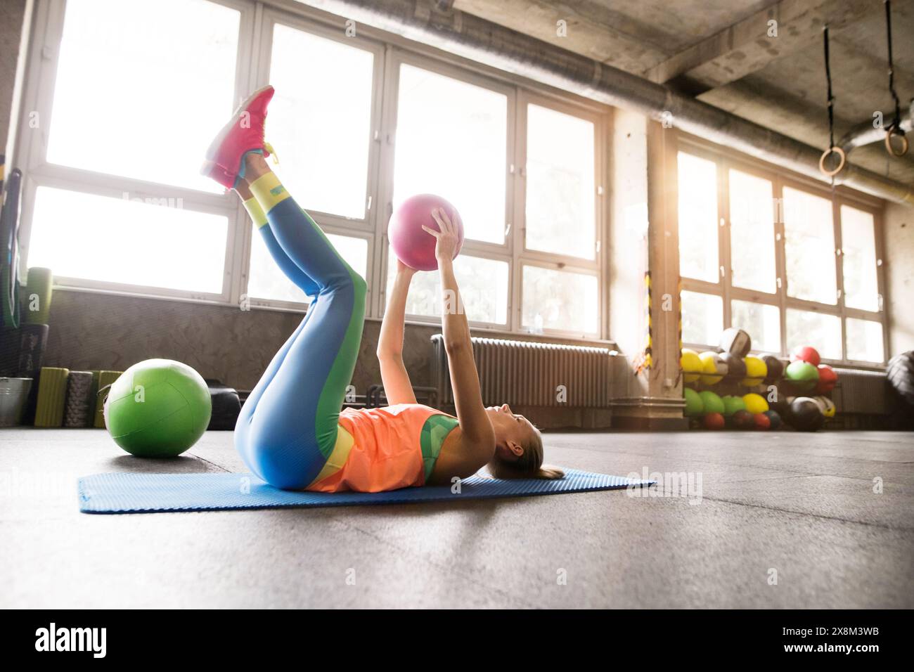 Beautiful sport woman exercising on gym mat with medicine ball. Routine ...