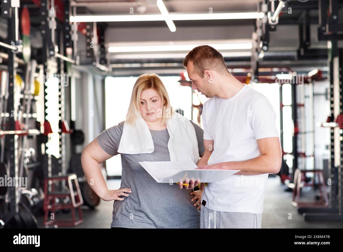 Overweight woman consulting with trainer, discussing daily workout plan ...