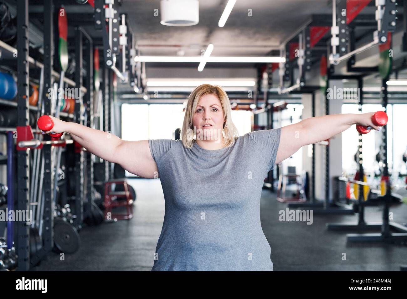 Overweight woman exercising in gym, using dumbbells Stock Photo - Alamy