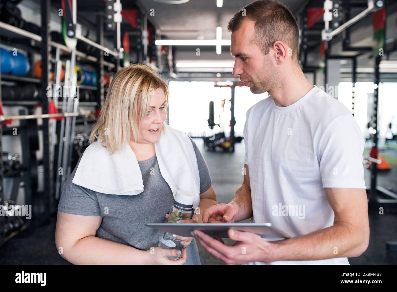 Overweight woman consulting with trainer, discussing daily workout plan ...