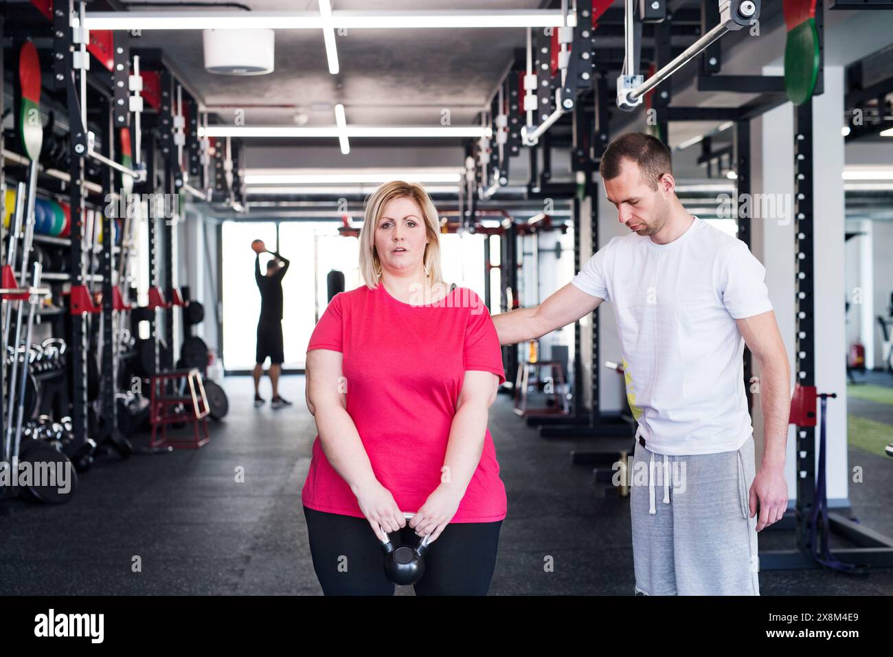 Overweight woman exercising in gym, using kettlebell. Personal trainer ...