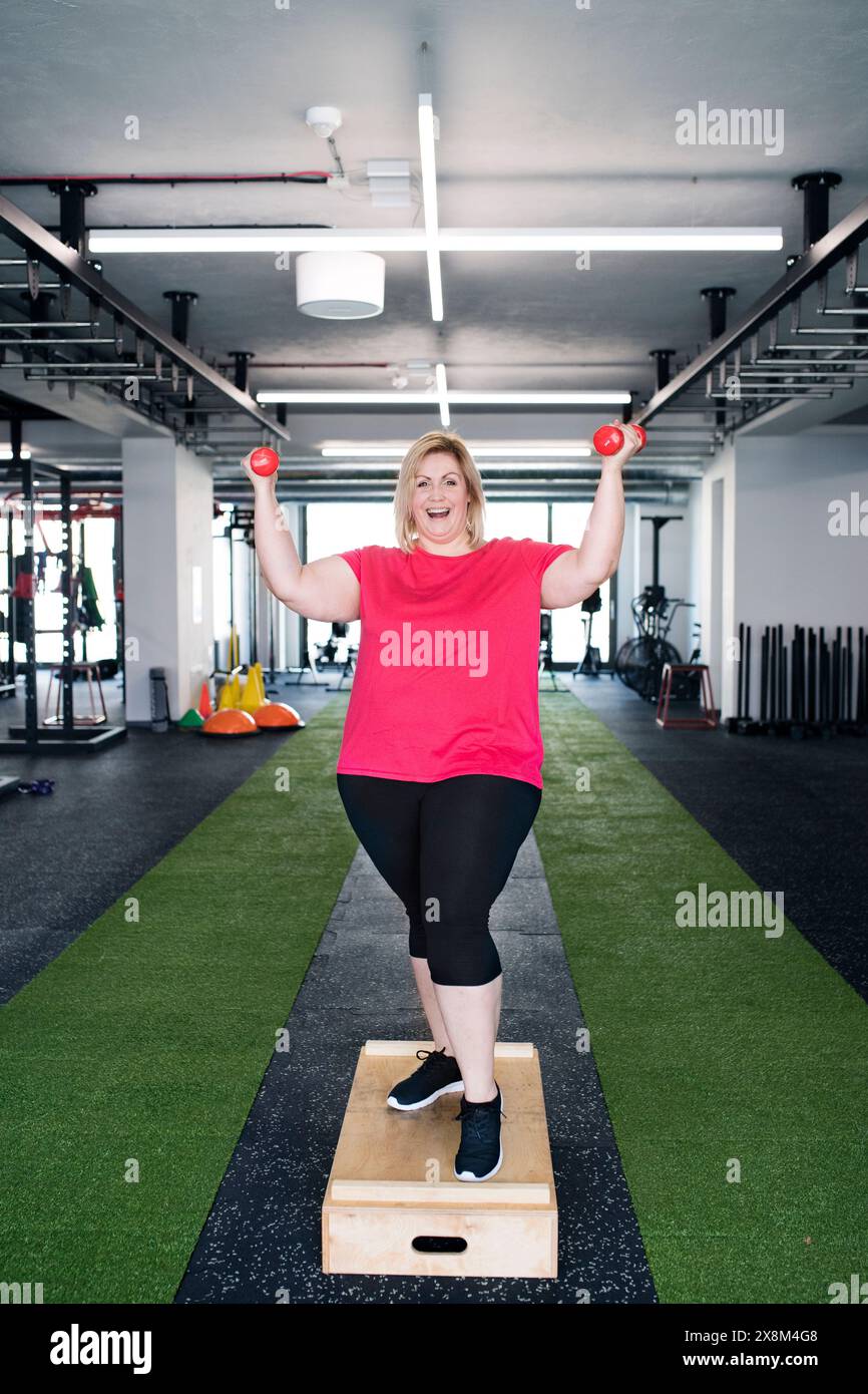 Overweight woman exercising in gym, using dumbbells Stock Photo - Alamy
