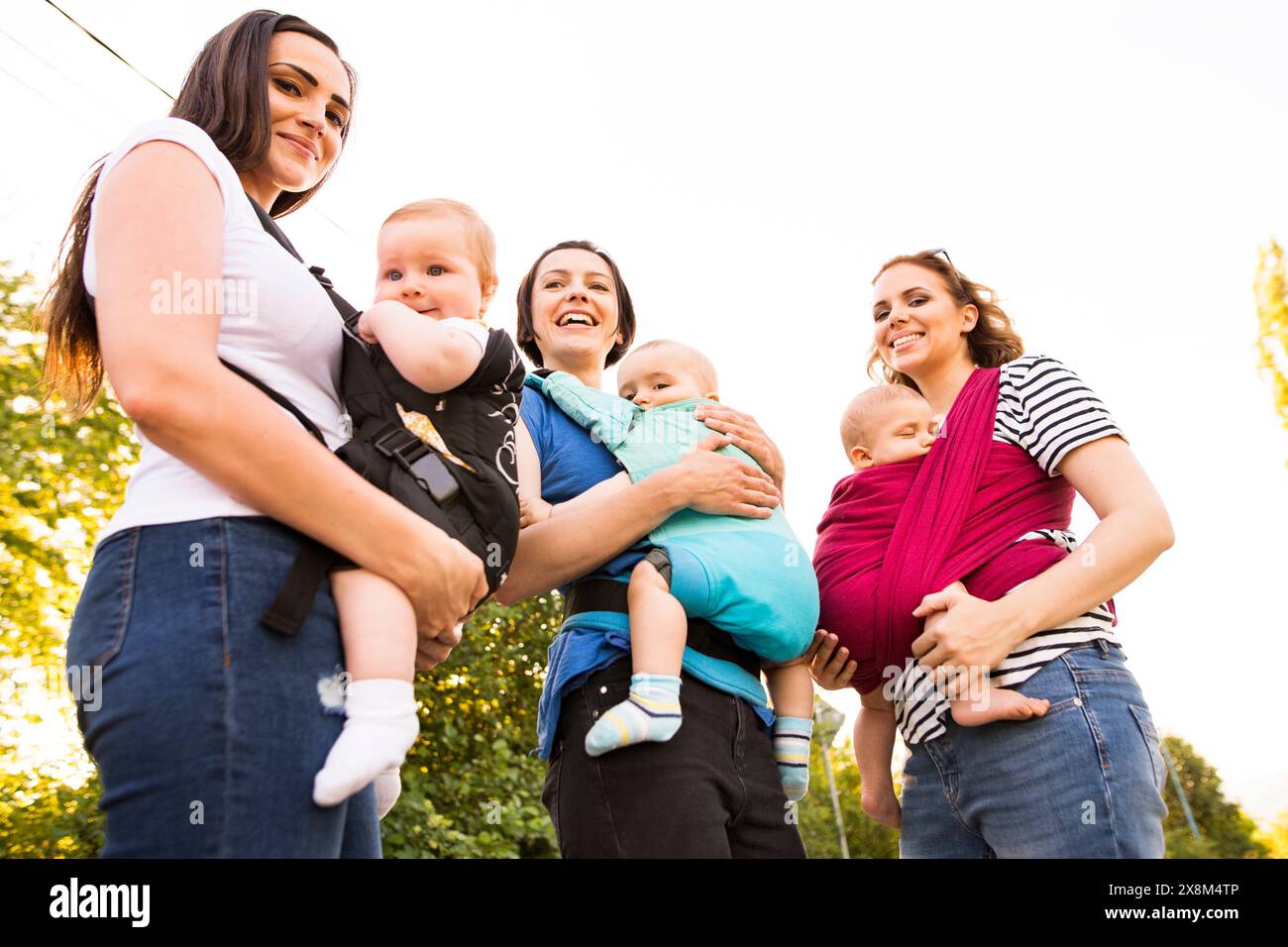 Mothers carrying babies in carriers, slings or wraps. Babywearing Stock ...