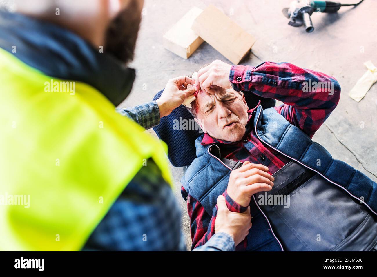 Colleague calling ambulance and giving first aid to injured worker, in ...