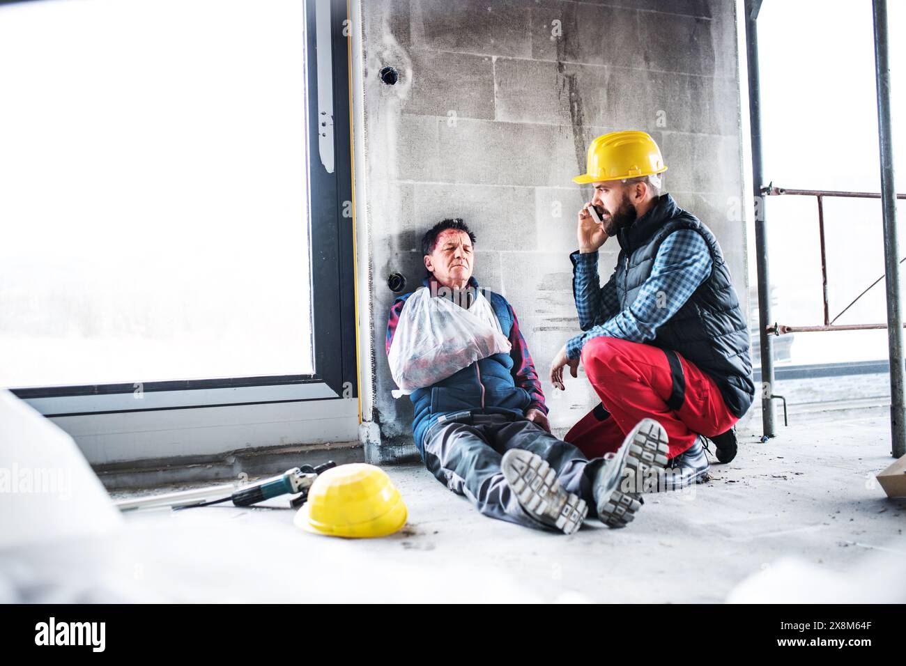 Colleague calling ambulance and giving first aid to injured worker, in ...