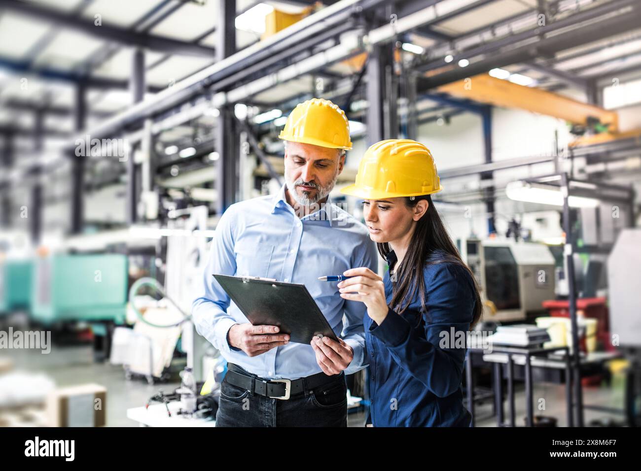 Two project managers standing in modern industrial factory ...