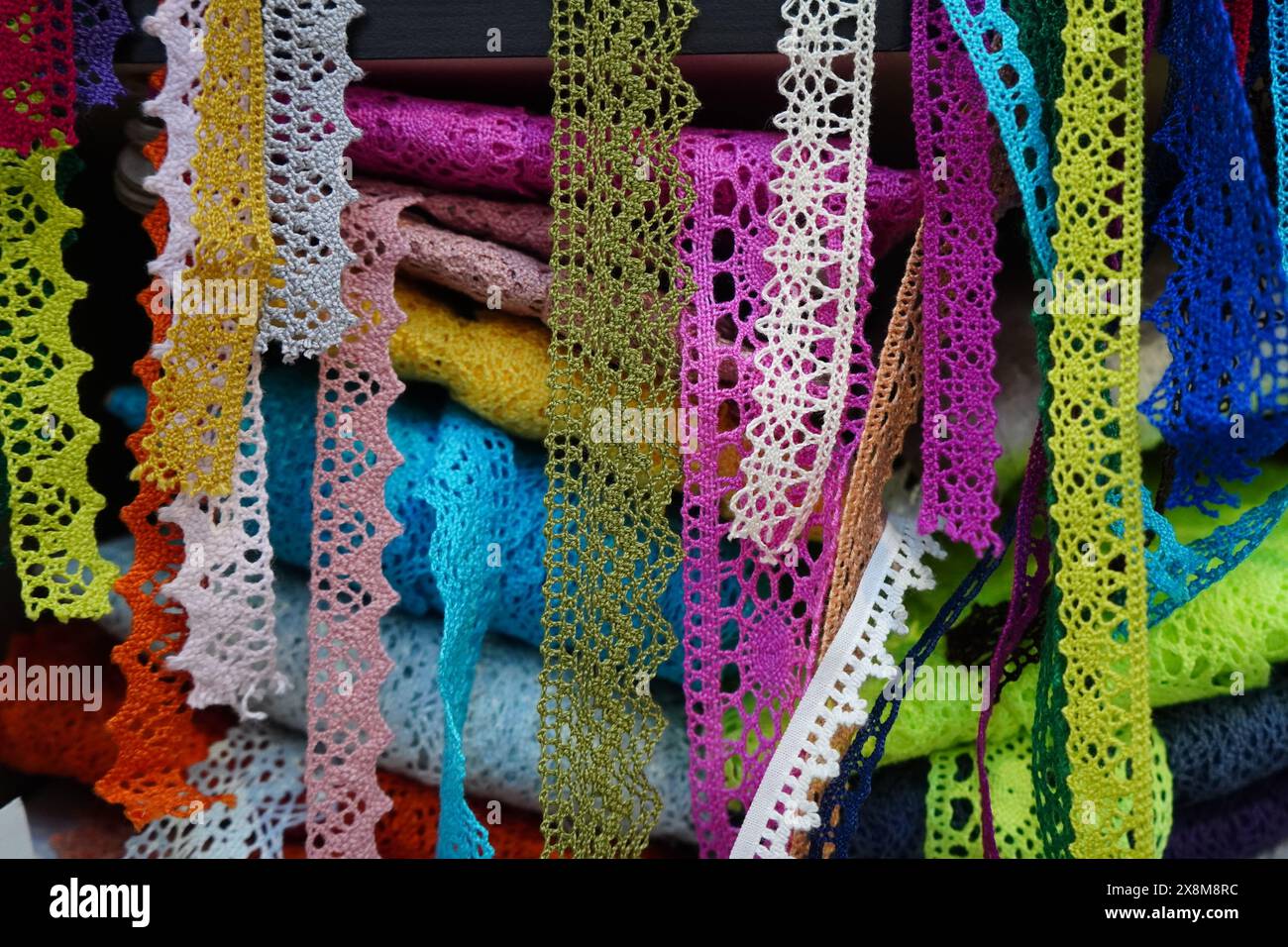 Lace ribbons in different colors and patterns hanging from rolls on ...
